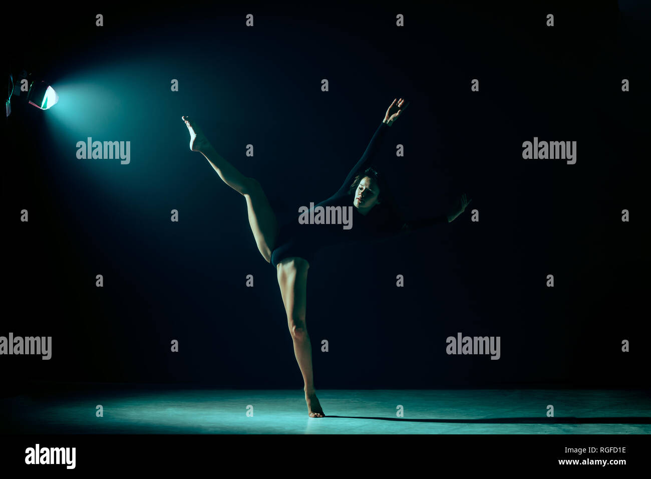 Young female ballet dancer dancing on neon lights studio background ...