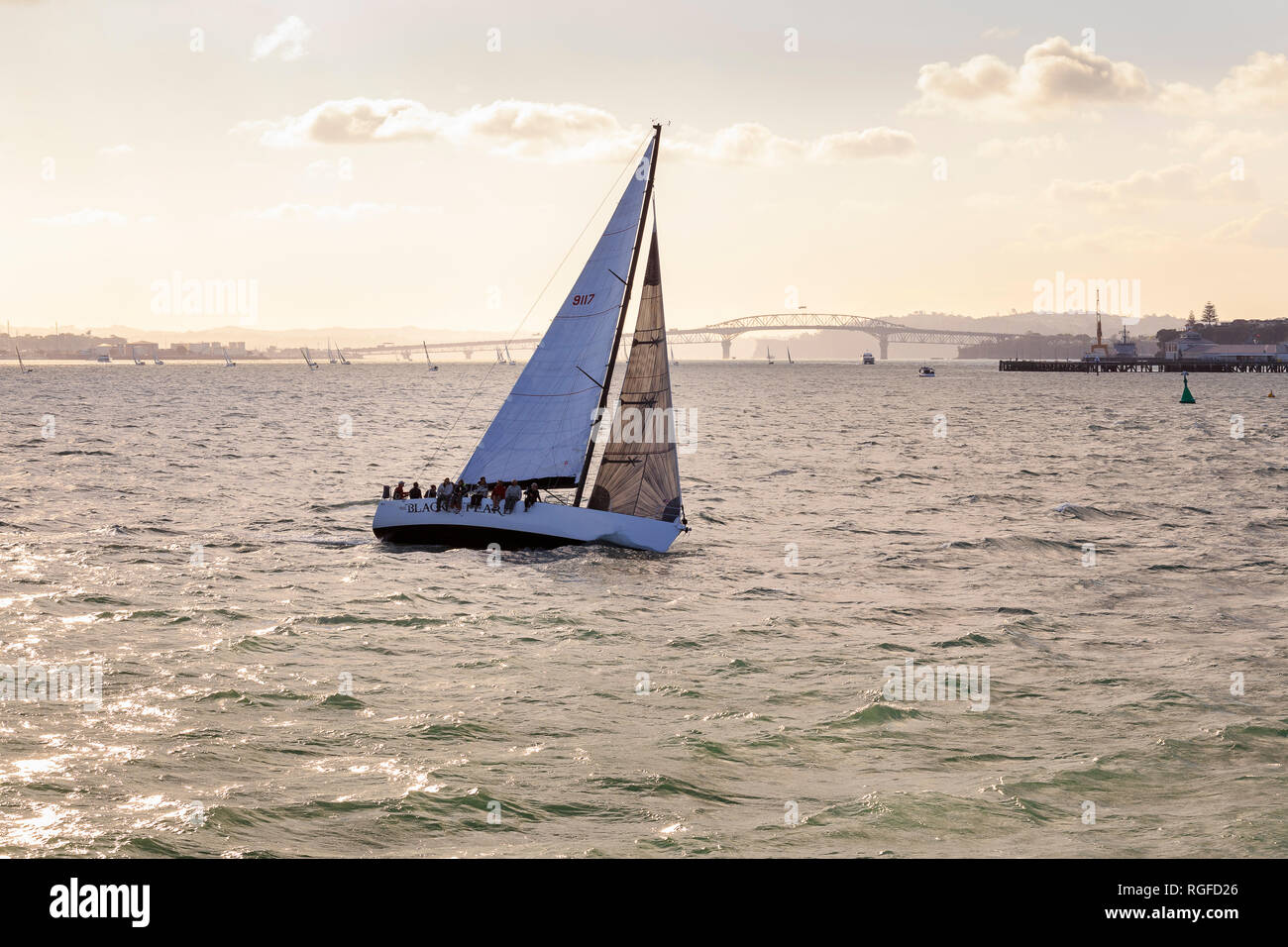 Sailing boat with people sitting with legs over the edge to balance the ...