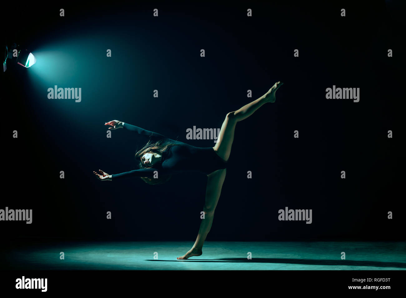 Young female ballet dancer dancing on neon lights studio background ...