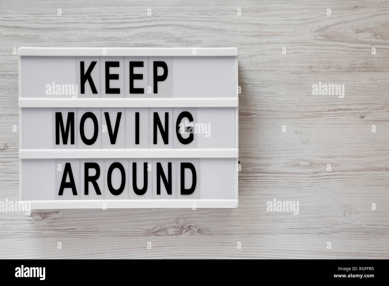 Modern board with text 'Keep moving around' over white wooden ...
