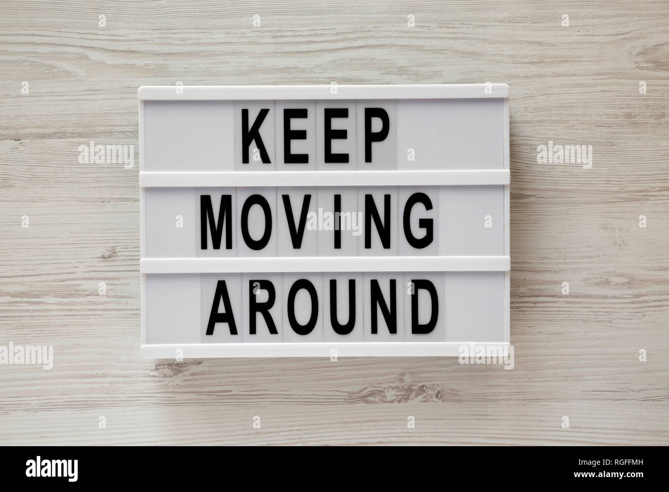 Modern board with text 'Keep moving around' over white wooden ...