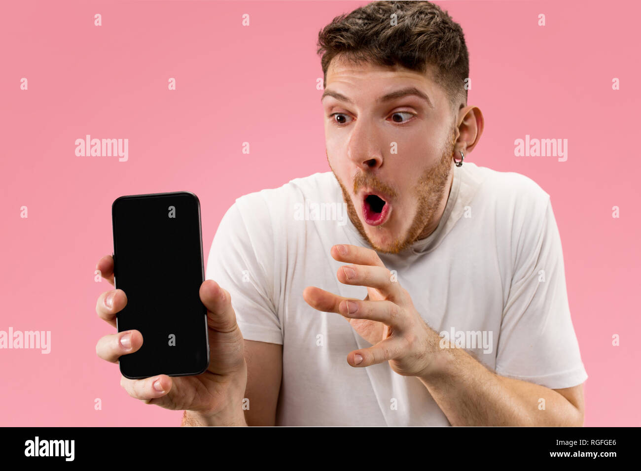 Young handsome man showing smartphone screen over pink background with ...