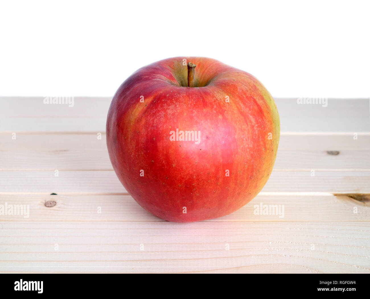 Big ripe red apple in beige wooden shelf on white background front view ...