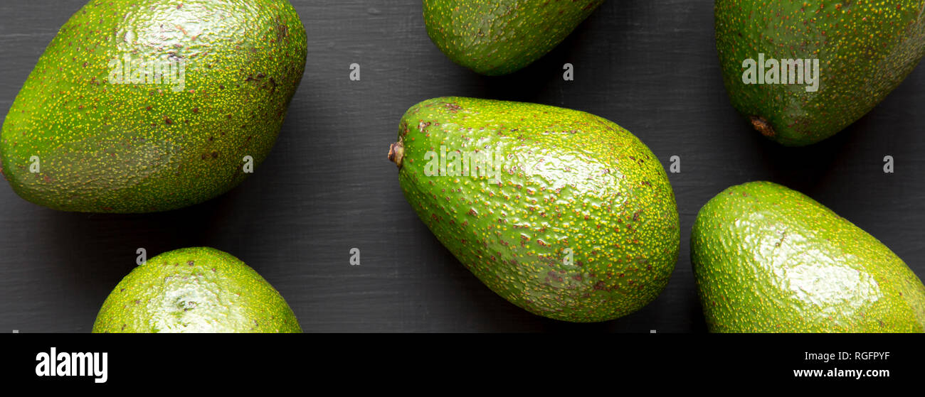 Whole avocados on black background, overhead view. Top view, from above ...