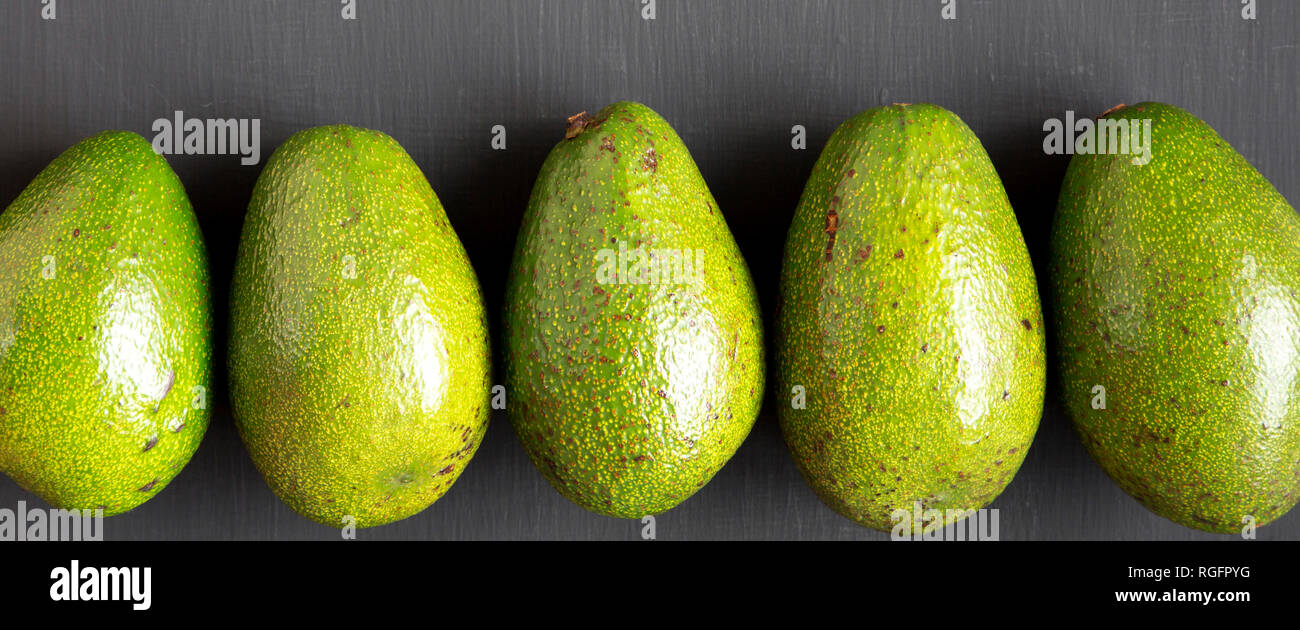 Whole avocados on black background, top view. Overhead, from above ...