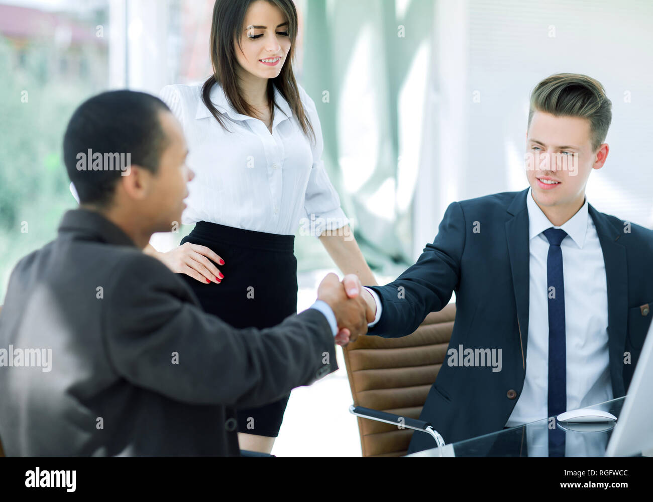 handshake of business partners sitting at a Desk Stock Photo - Alamy