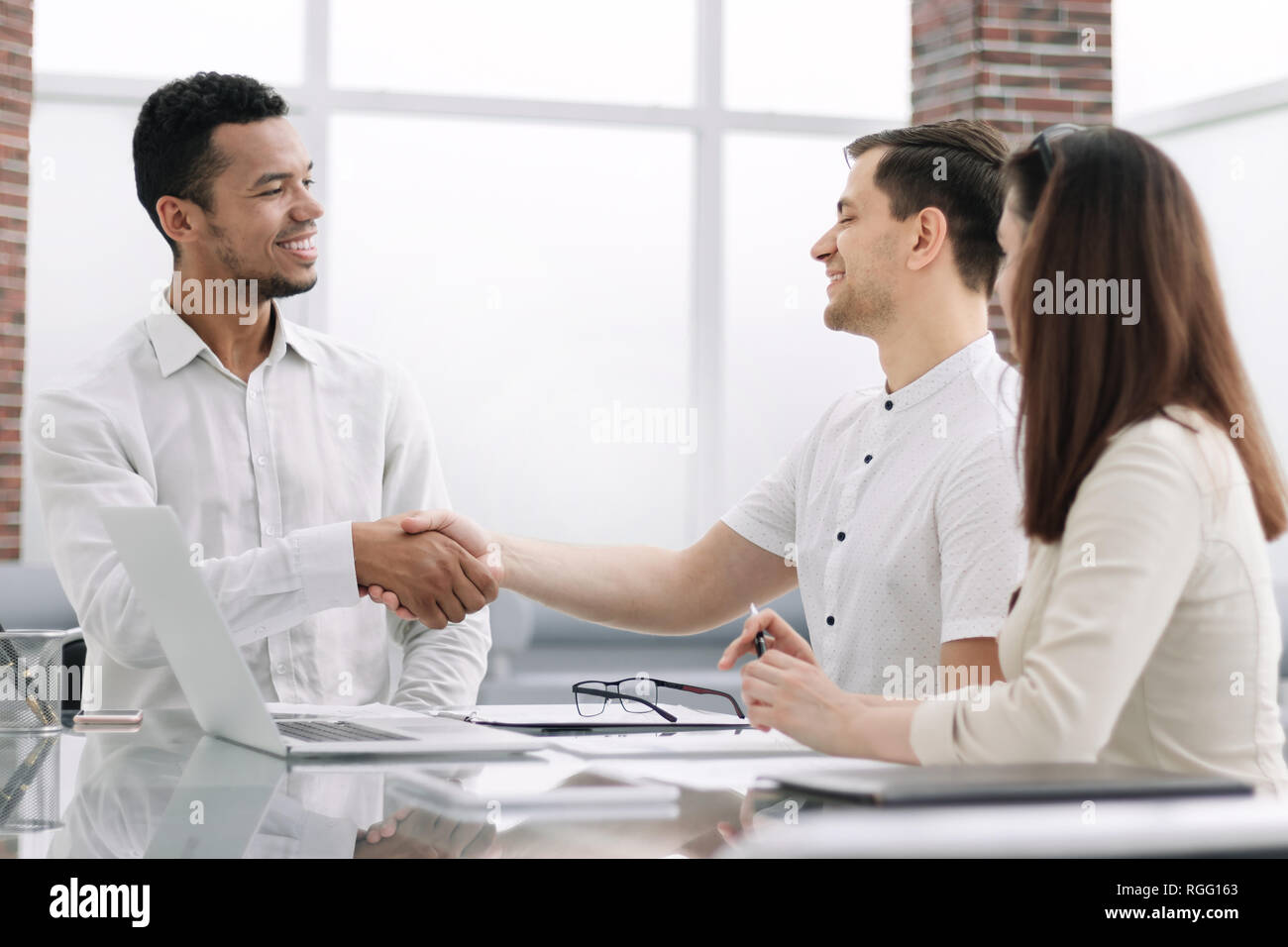 handshake business partners sitting at the office Desk Stock Photo - Alamy