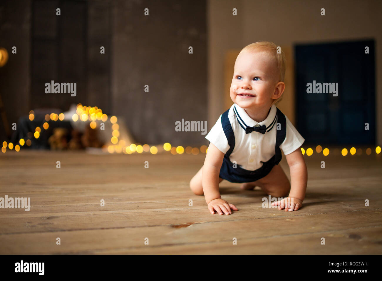 Smiling baby boy crawls at the floor against background of garland of ...