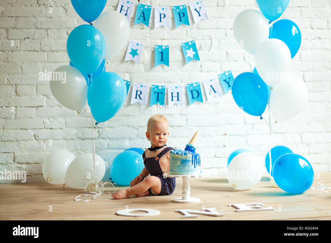 One year old boy is celebrating his first birthday among a lot of blue ...