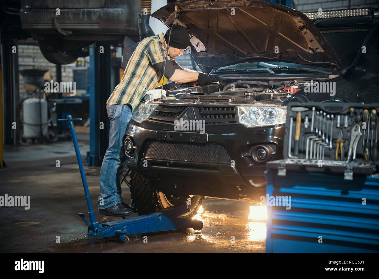Car repair service. Mechanic man standing by the car with open hood and ...