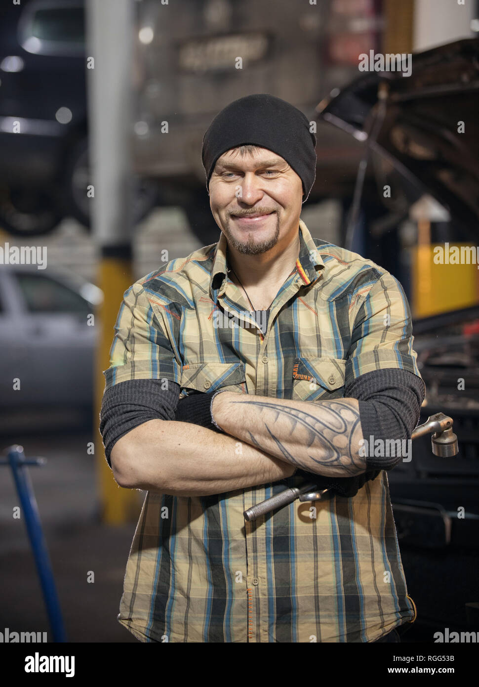 Car service. Brutal mechanic man standing by the car and smiles Stock ...