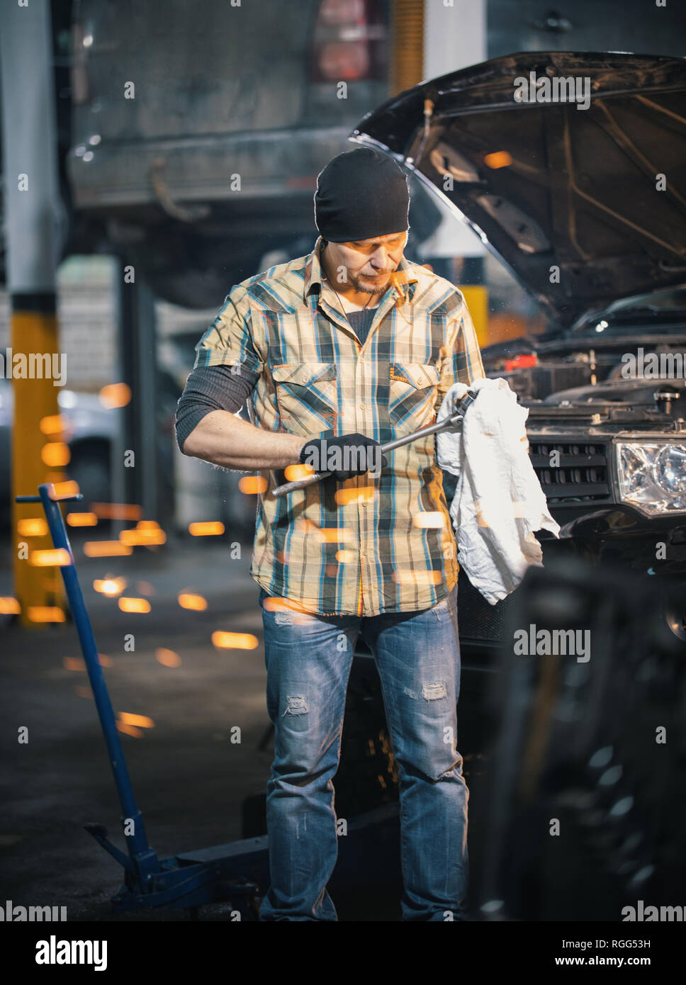 Car service. Mechanic man standing by the car and wipes off the tool ...