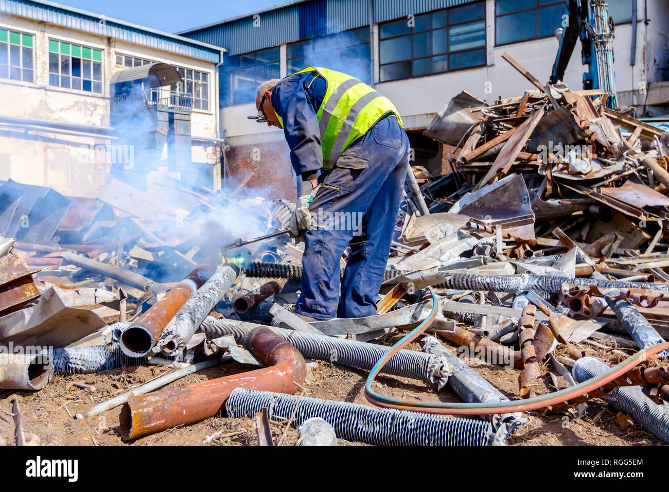 Worker is cutting waste metal with gas by mixing oxygen and acetylene ...