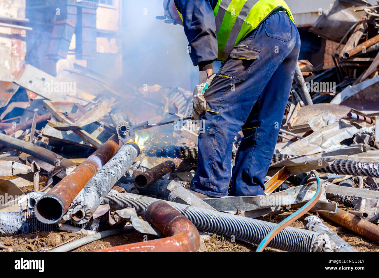 Worker is cutting waste metal with gas by mixing oxygen and acetylene ...