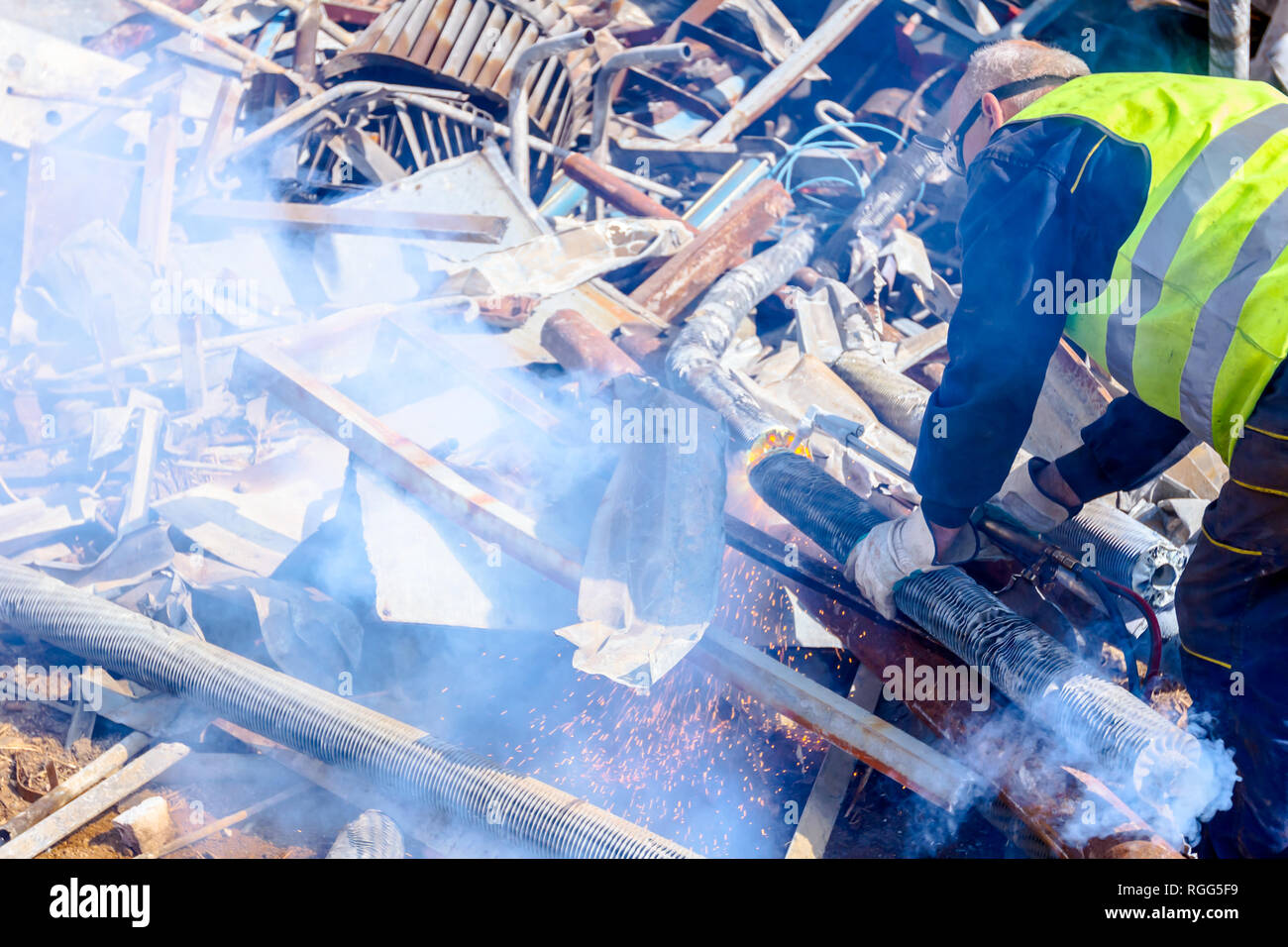 Worker is cutting waste metal with gas by mixing oxygen and acetylene ...
