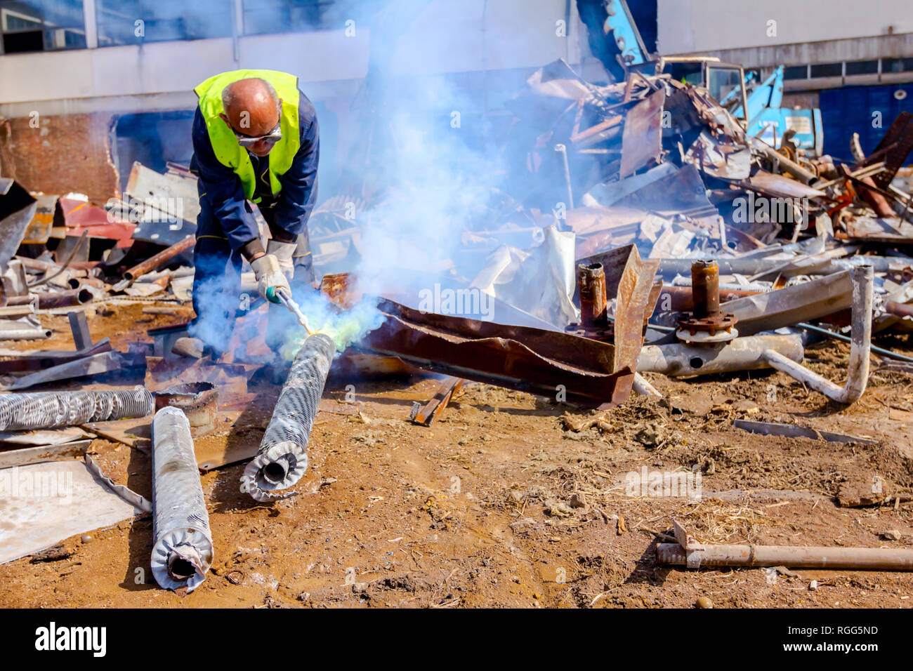 Worker is cutting waste metal with gas by mixing oxygen and acetylene ...