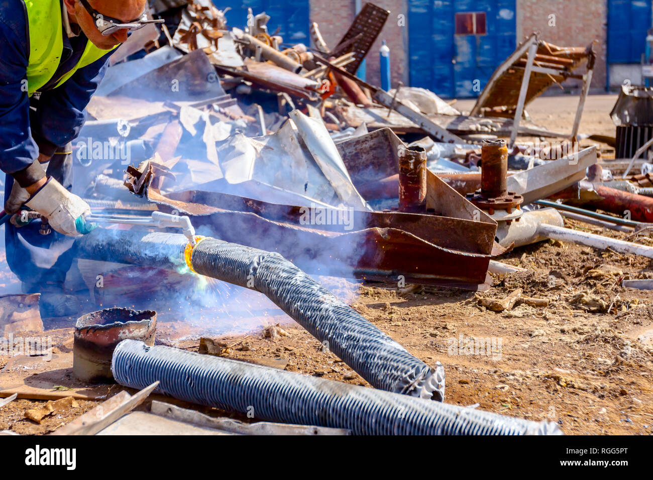 Worker is cutting waste metal with gas by mixing oxygen and acetylene ...
