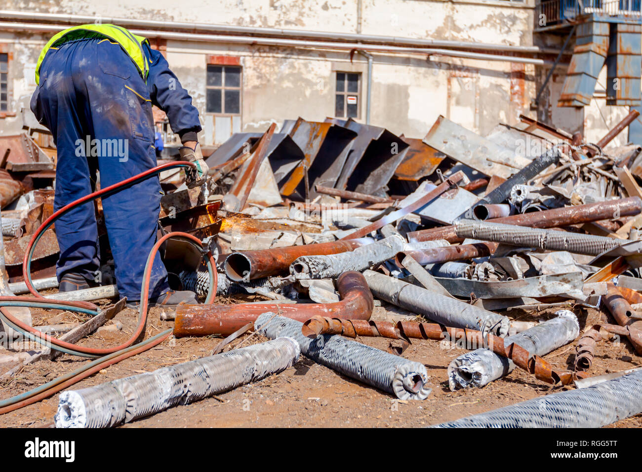 Worker is cutting waste metal with gas by mixing oxygen and acetylene ...