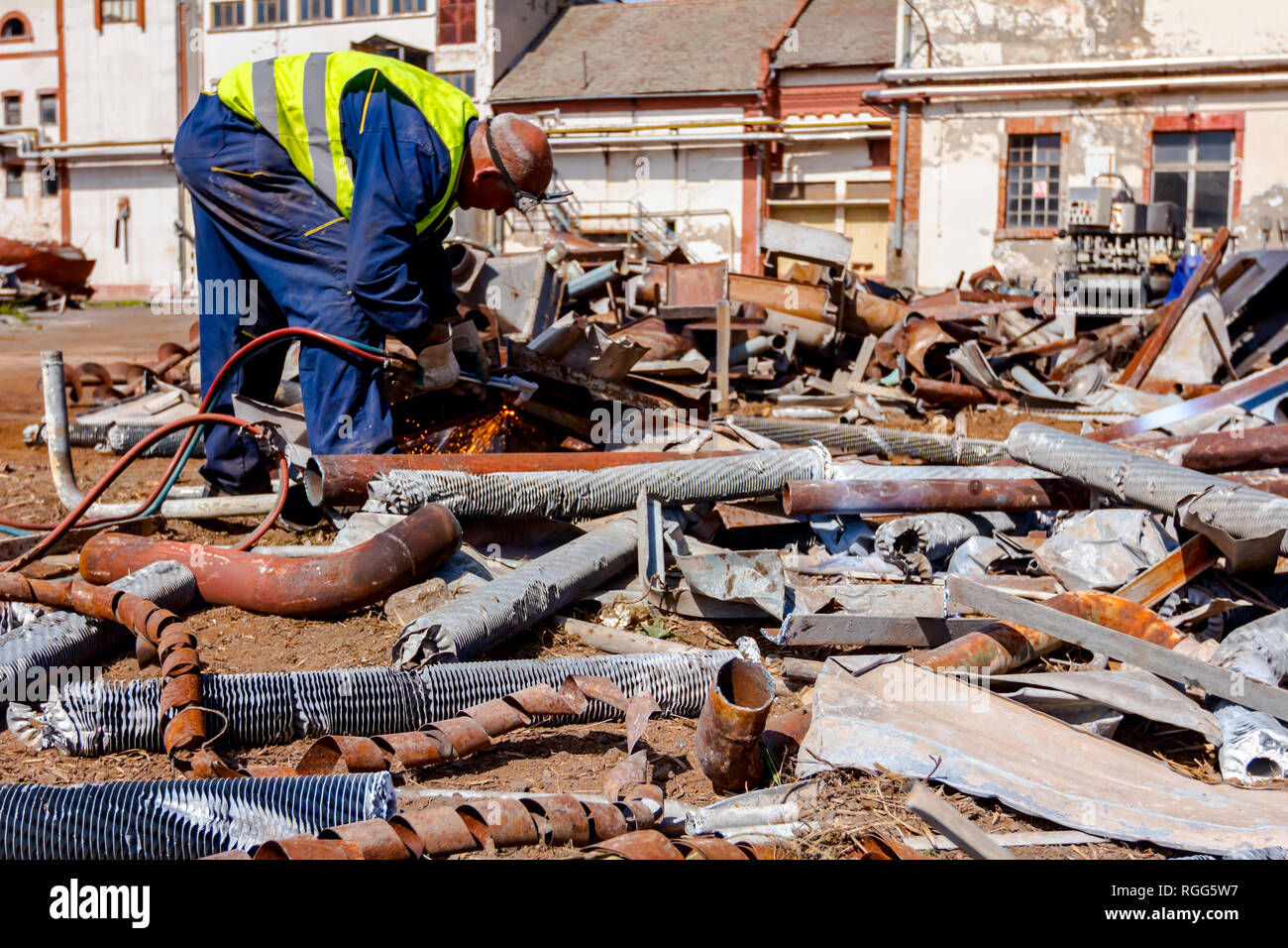 Worker is cutting waste metal with gas by mixing oxygen and acetylene ...
