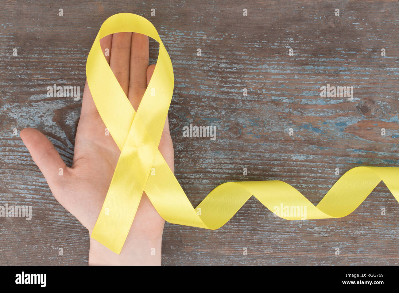 yellow ribbon-childhood cancer awareness symbol on the wooden ...