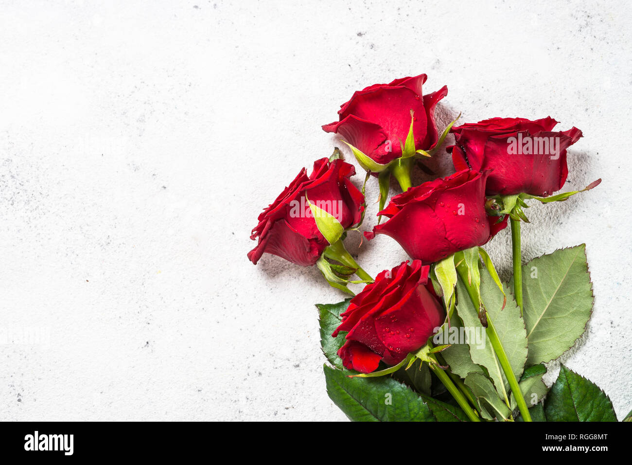 Red roses flower bouquet on white stone table. Top view with copy space ...