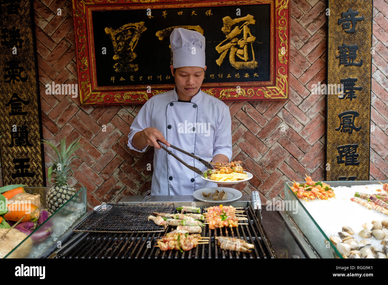 Cook grilling meat and shellfish at a chinese restaurant Stock Photo ...