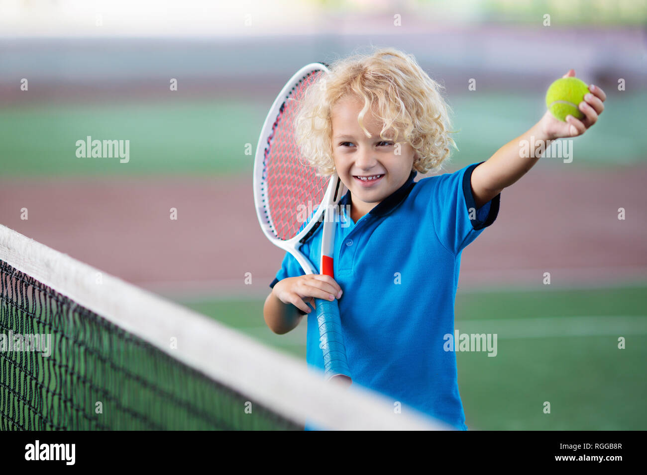 Child playing tennis on indoor court. Little boy with tennis racket and ...