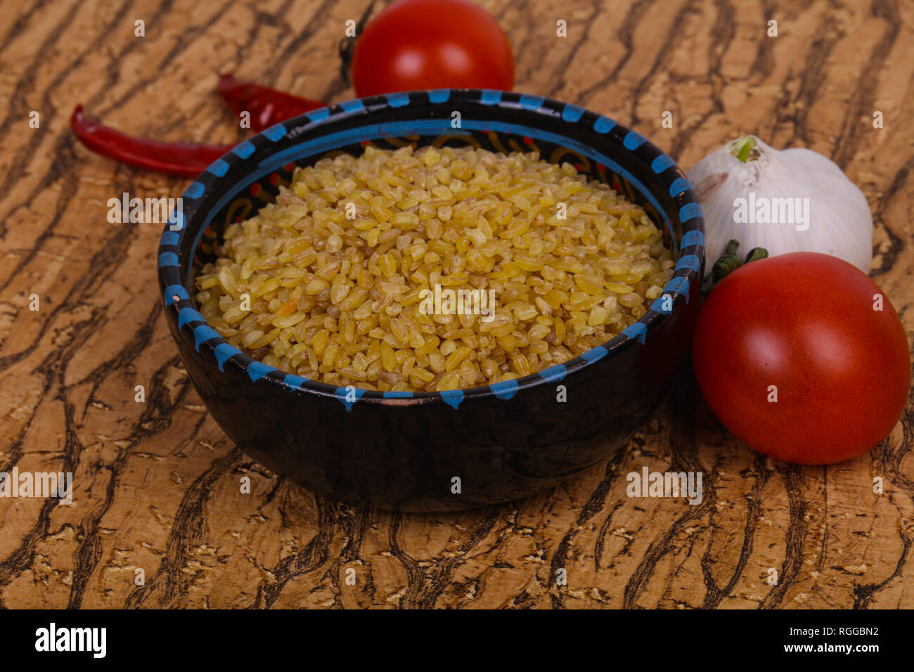 Raw golden bulgur in the bowl with tomatoes and garlic Stock Photo - Alamy