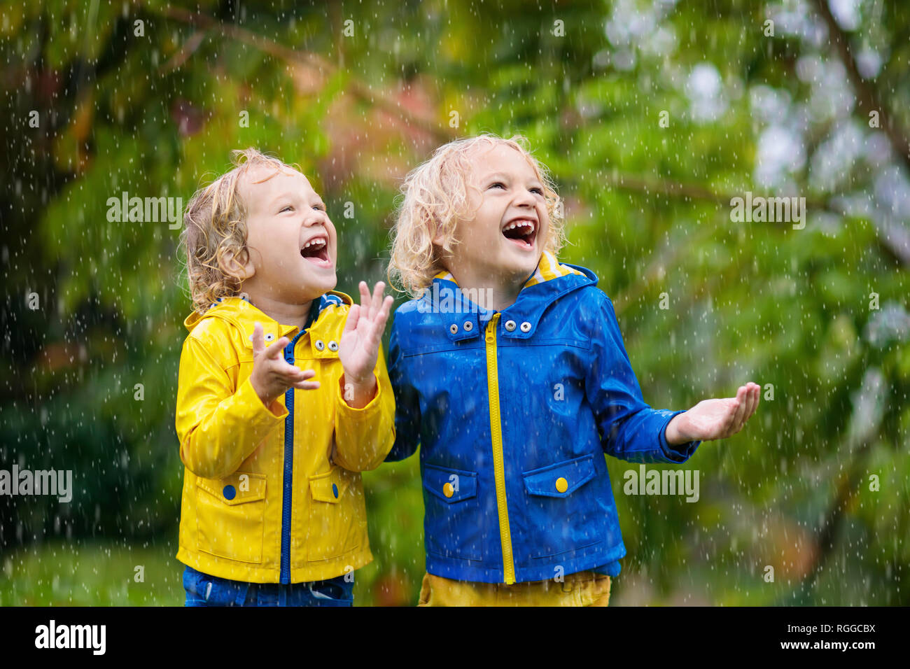 Kids play in autumn rain. Child playing outdoor on rainy day. Little ...
