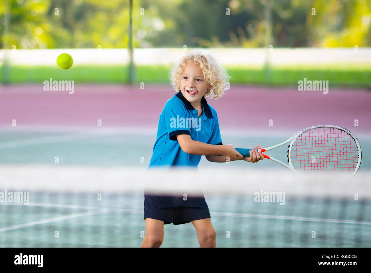 Child playing tennis on indoor court. Little boy with tennis racket and ...