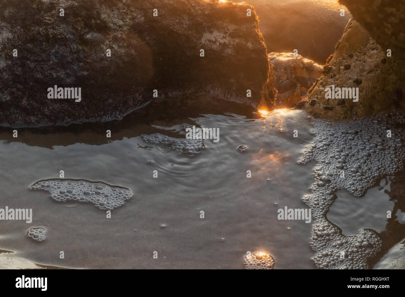Marine swimming pool formed by rocks on the beach with beautiful sunset ...