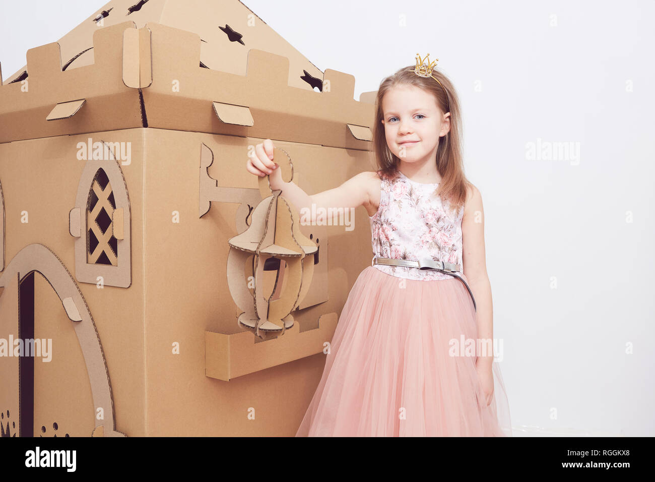 Little princess in crown play with her cardboard castle. True emotion ...