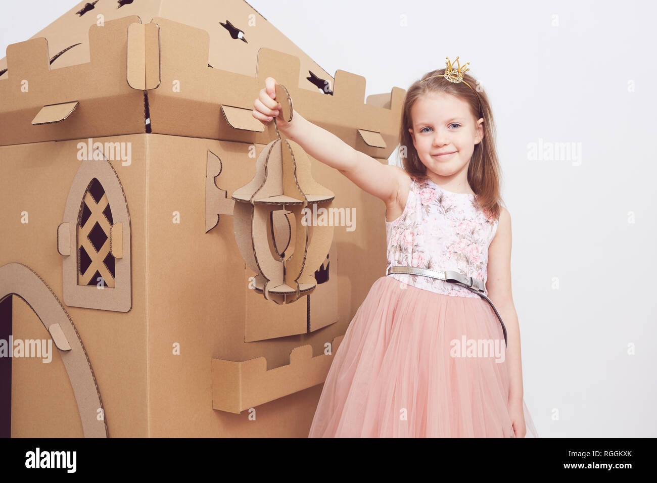 Little princess in crown play with her cardboard castle. True emotion ...