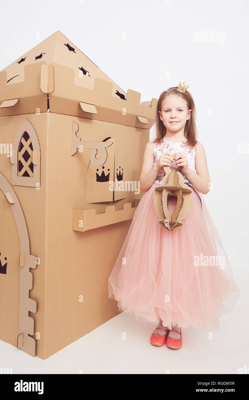 Little princess in crown play with her cardboard castle. True emotion ...