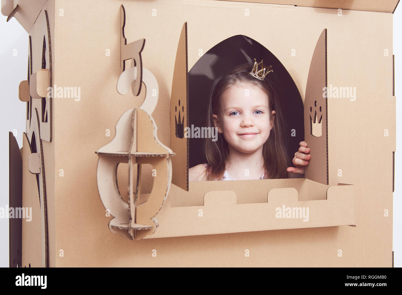 Little princess in crown play with her cardboard castle. True emotion ...