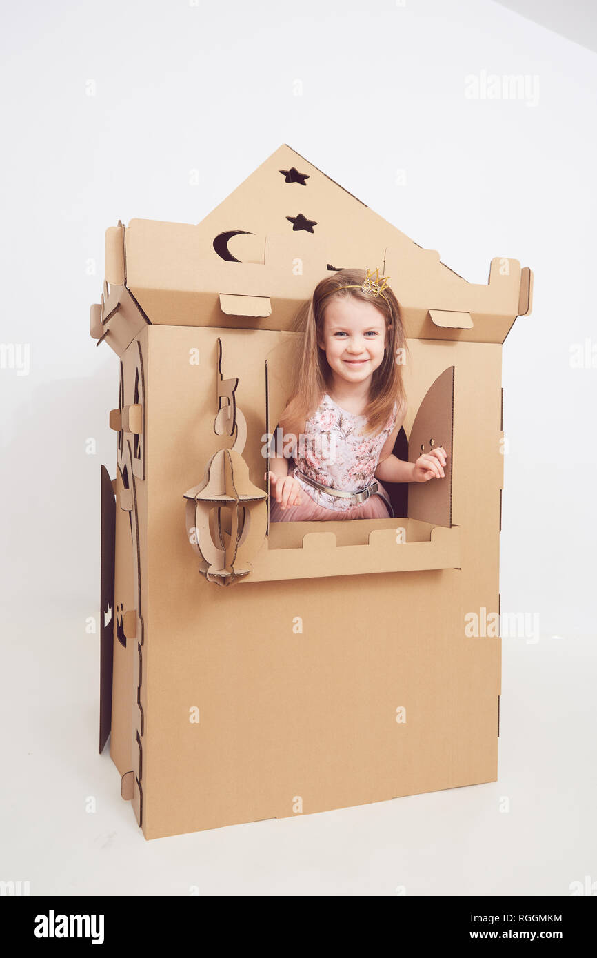 Little princess in crown play with her cardboard castle. True emotion ...