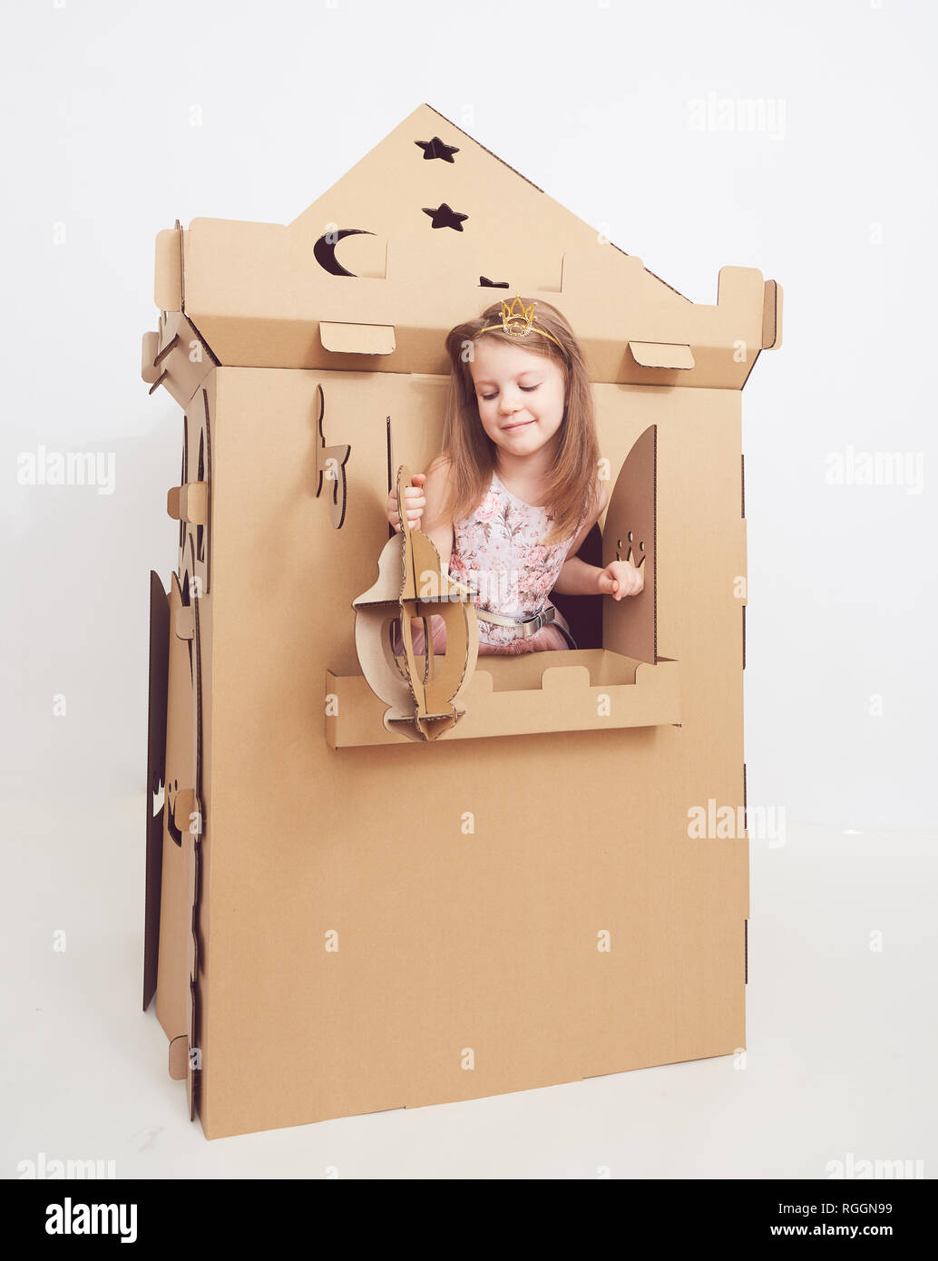 Little princess in crown play with her cardboard castle. True emotion ...