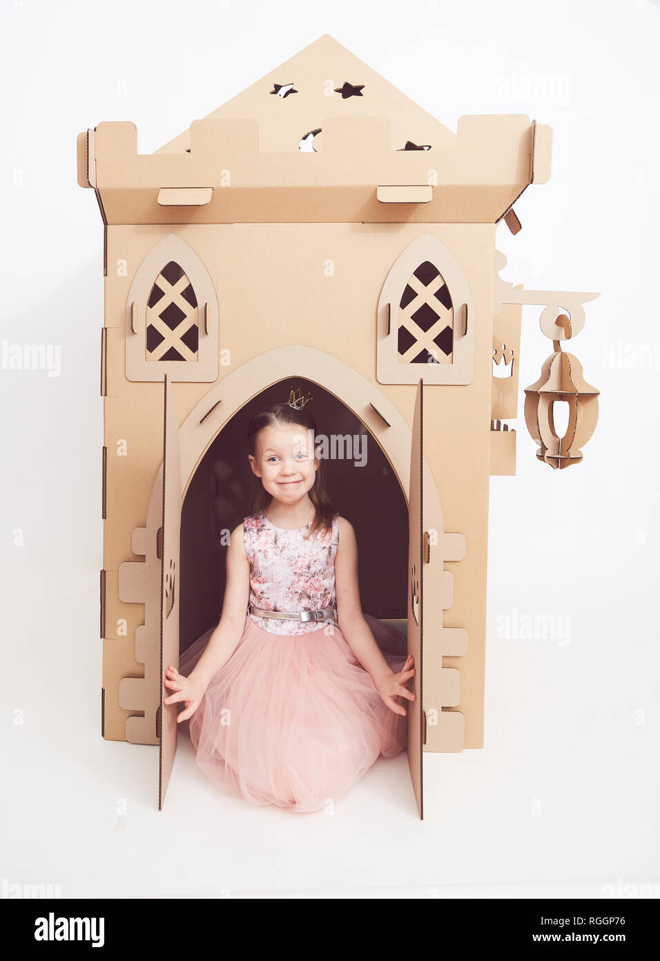 Little princess in crown play with her cardboard castle. True emotion ...