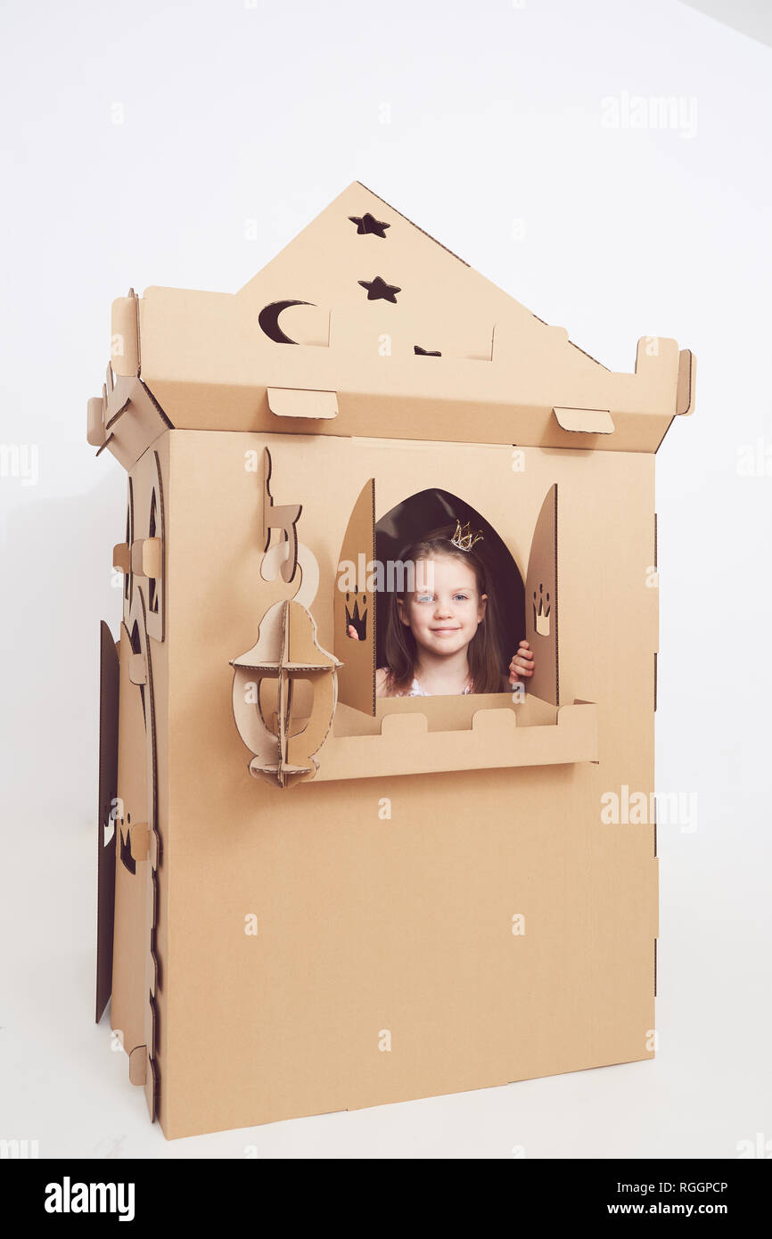 Little princess in crown play with her cardboard castle. True emotion ...