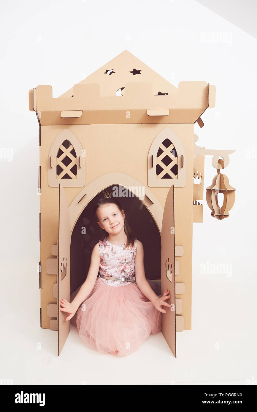 Little princess in crown play with her cardboard castle. True emotion ...