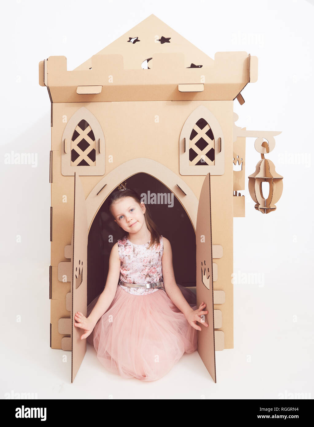Little princess in crown play with her cardboard castle. True emotion ...