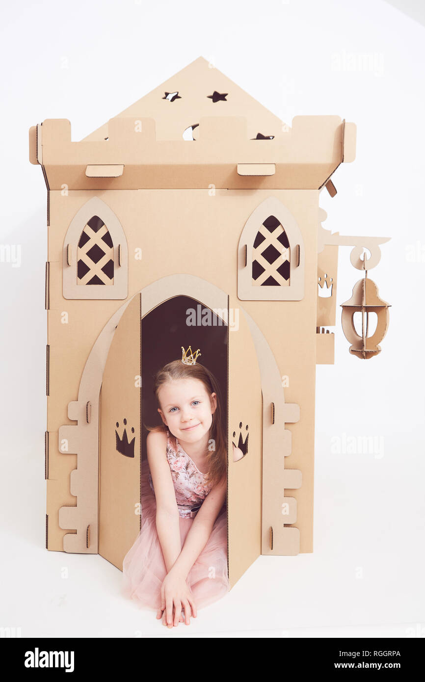 Little princess in crown play with her cardboard castle. True emotion ...
