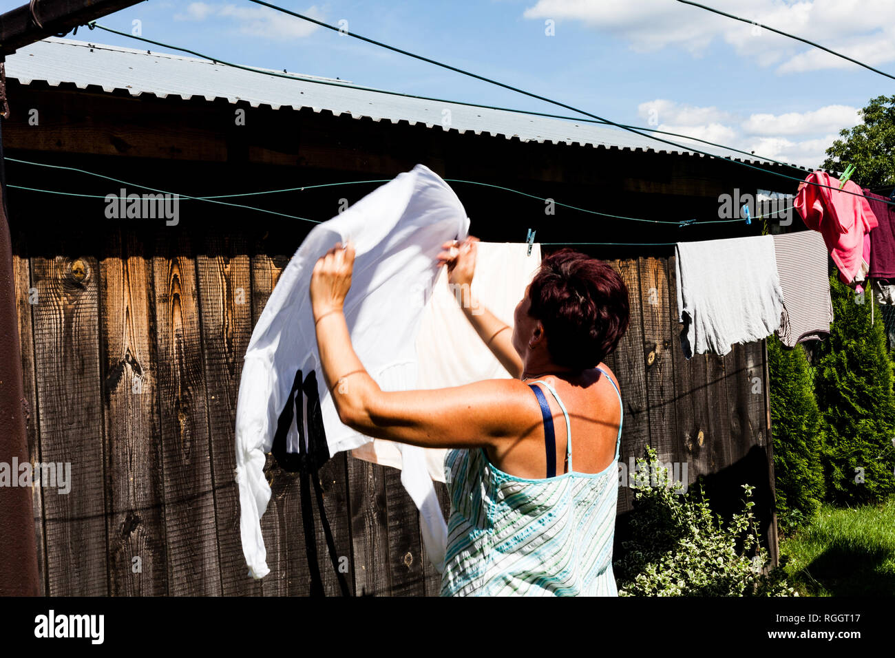 Back view of a woman hanging the white fabric over the string in one ...