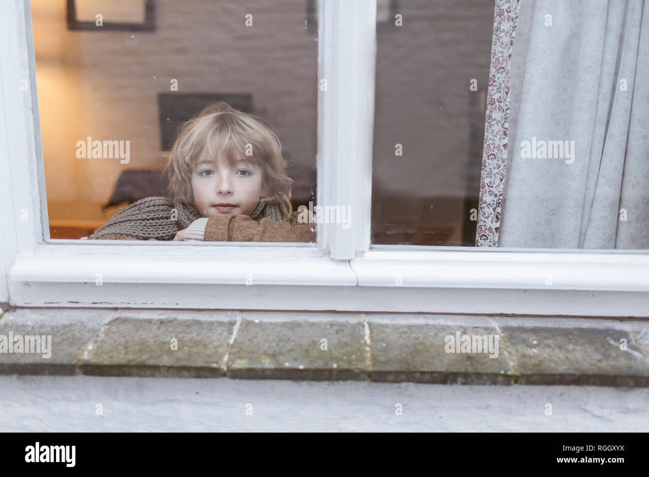 Portrait of pensive boy looking out of window Stock Photo - Alamy