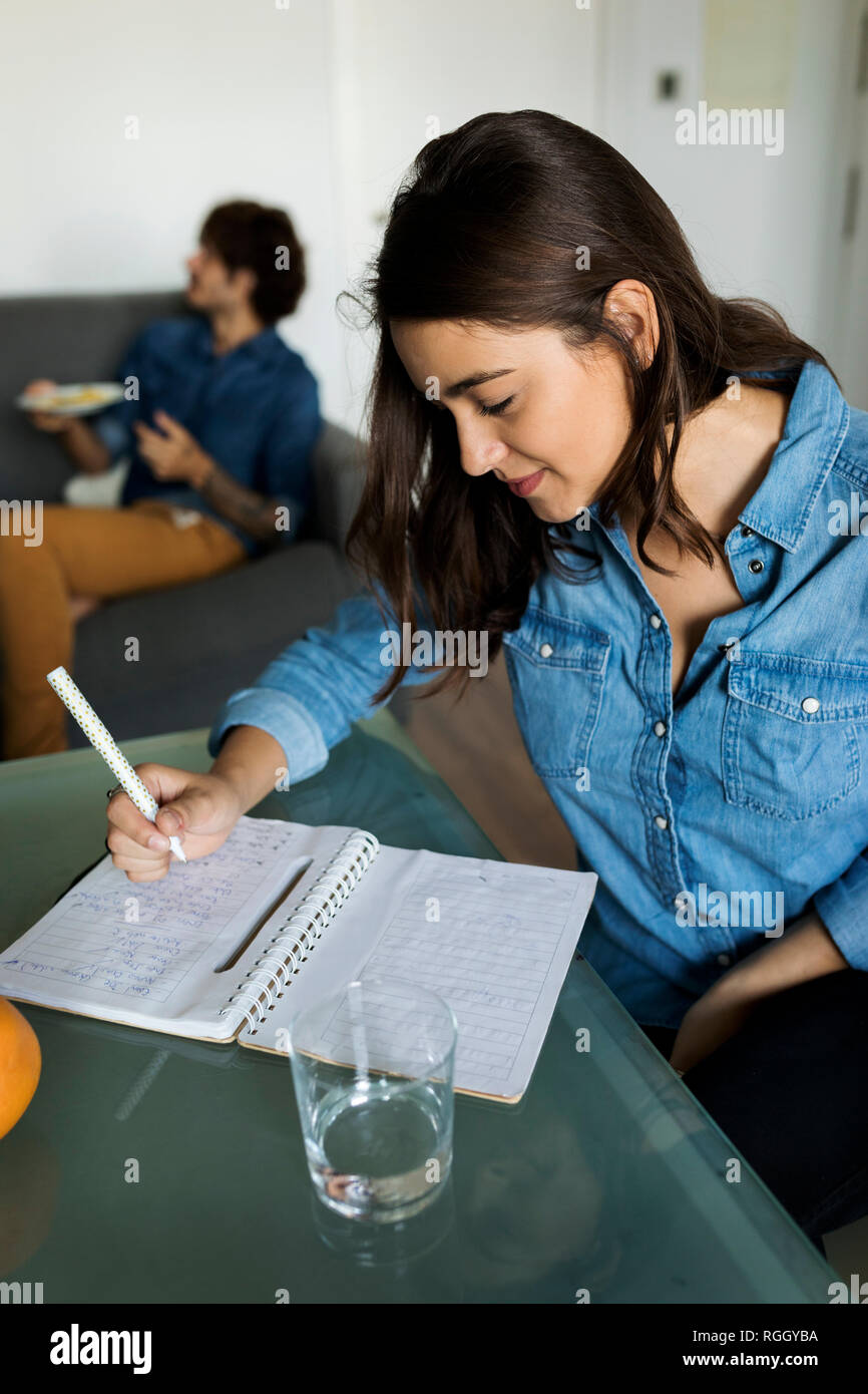 Woman taking notes at dining table with friend in background Stock ...