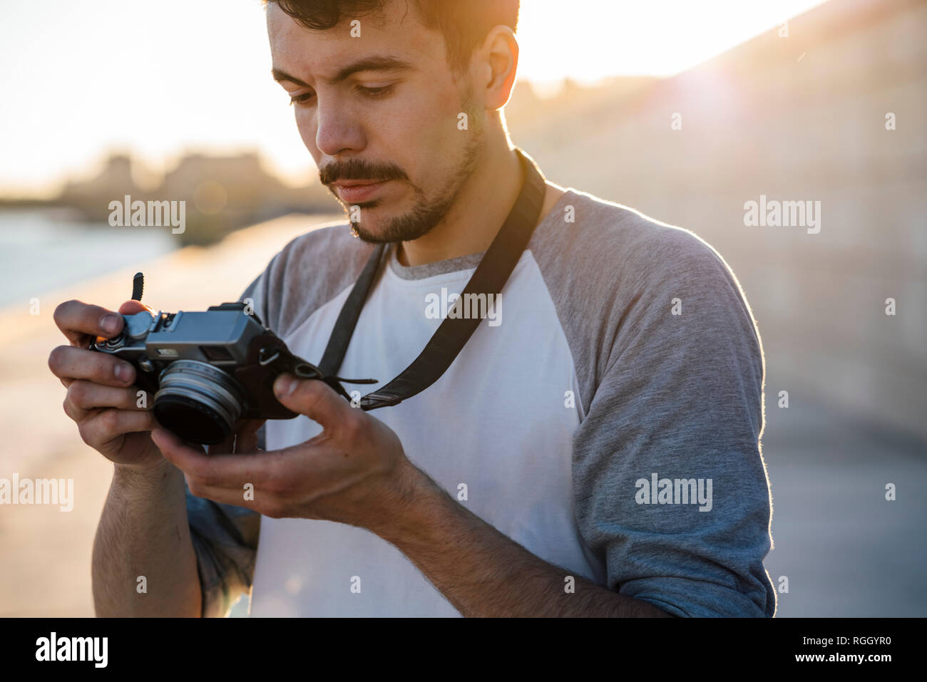 Young man looking at camera on waterfront promenade at the riverside ...