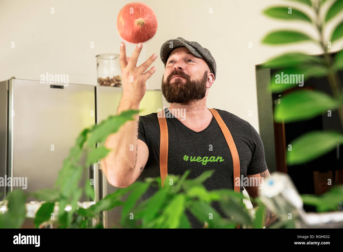 Vegan man playing with a pumpkin in his kitchen Stock Photo - Alamy
