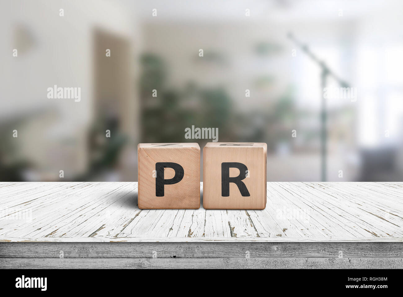 PR sign on a worn table in a bright room with green plants and a ...