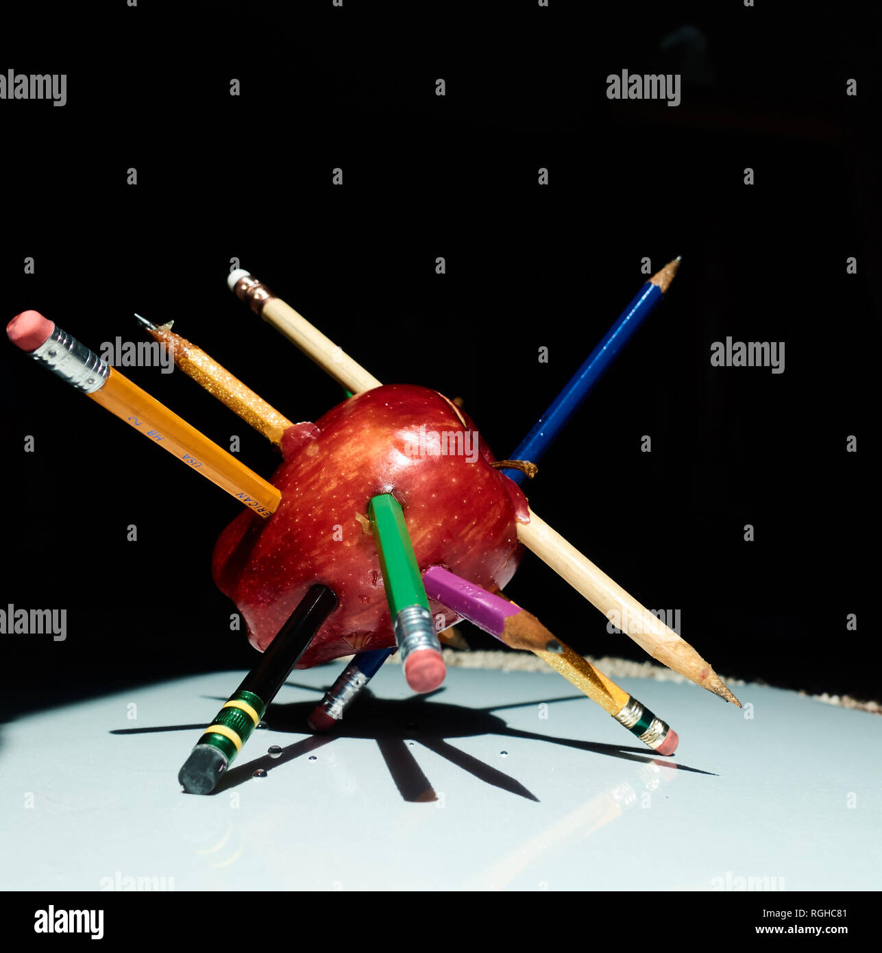 Red apple skewered with pencils on white background Stock Photo - Alamy