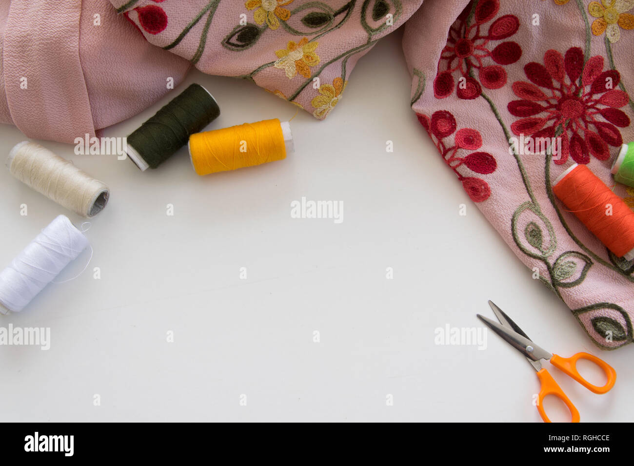 Top view of embroidered cloth and colorful threads on white background ...